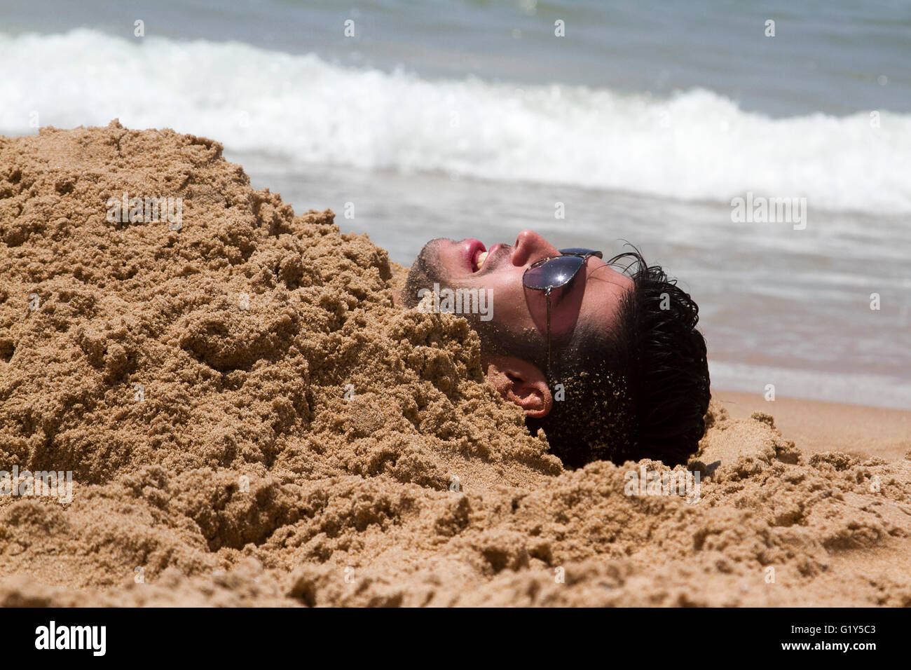 Beirut, Lebanon. 21st May, 2016. A Beachgoer soaks up the sun buried ...