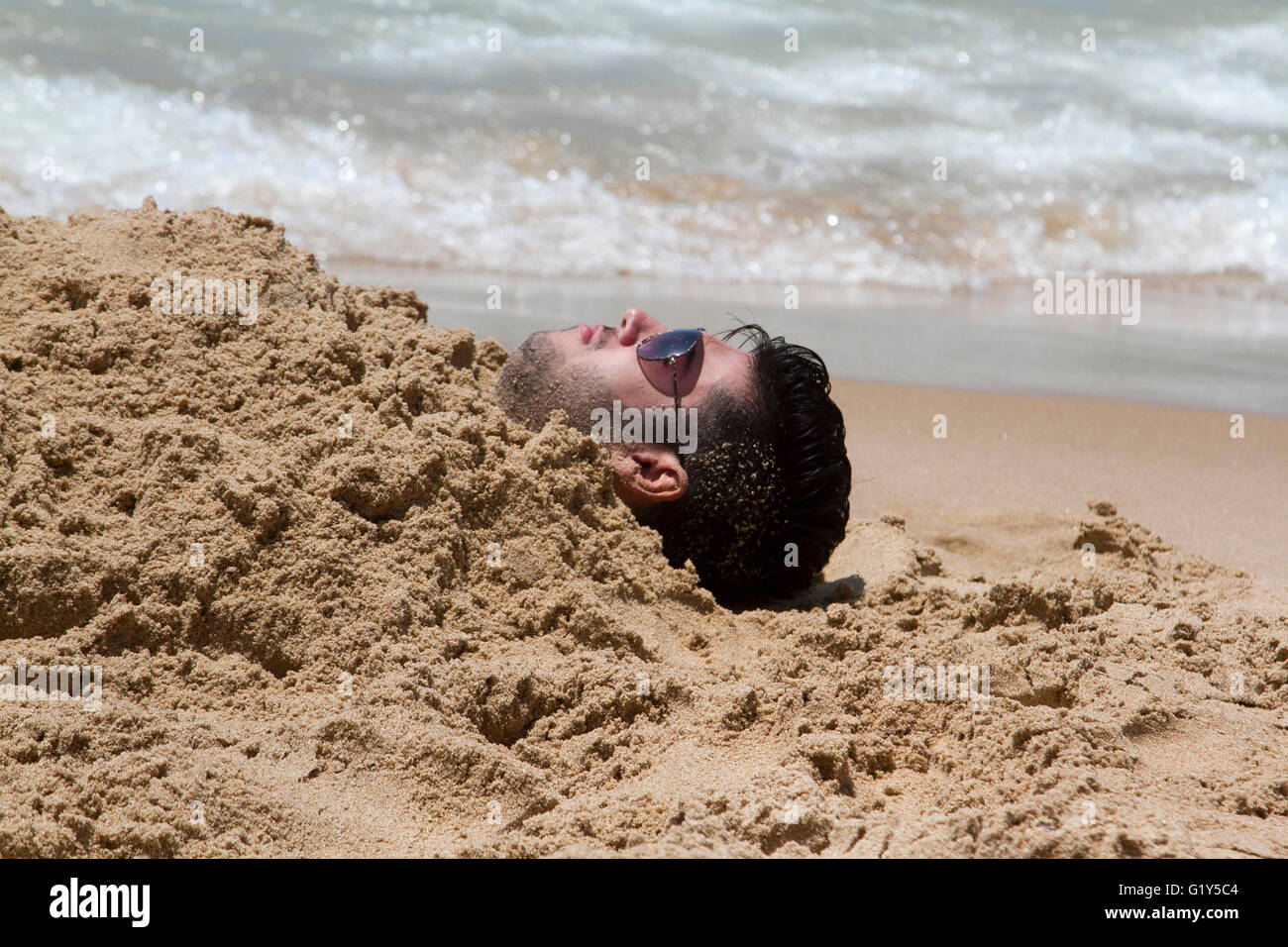 Beirut, Lebanon. 21st May, 2016. A Beachgoer soaks up the sun buried ...