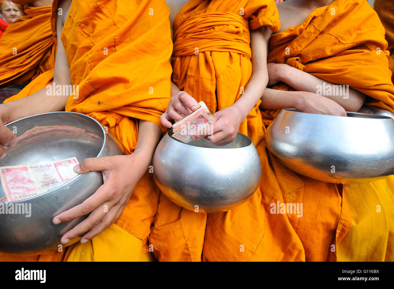 Nepalese Buddhist monks await devotees by holding Inscribed pot for the ...