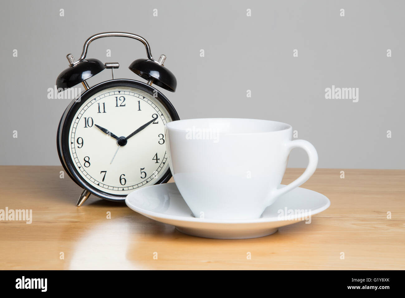 Alarm and cup of tea on wooden tabel Stock Photo - Alamy