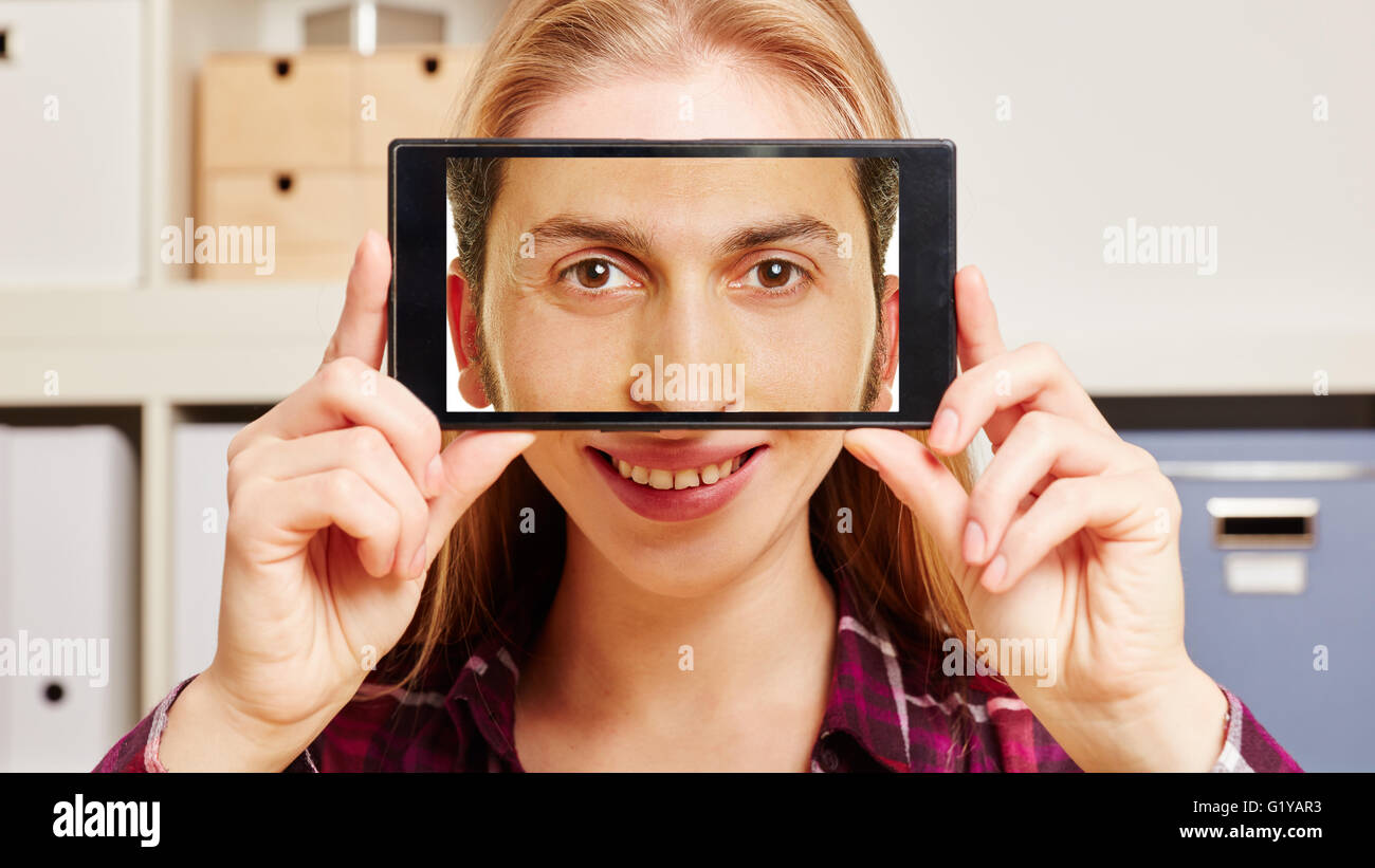 Hands holding a smartphone with the face of a man in front of the head ...