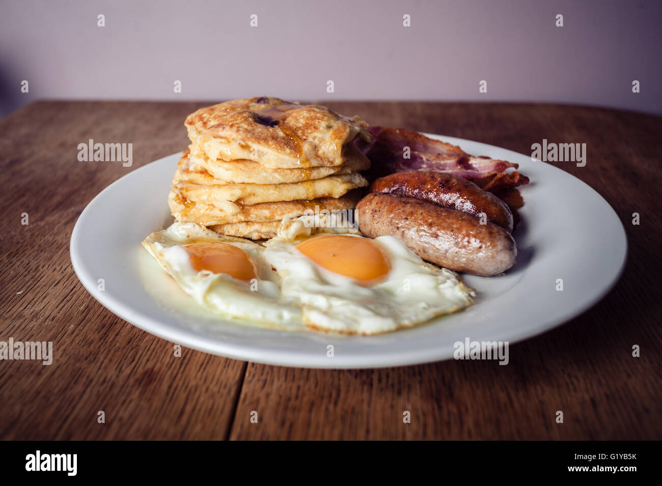 A breakfast with short stack of pancakes, bacon, eggs and sausage Stock ...