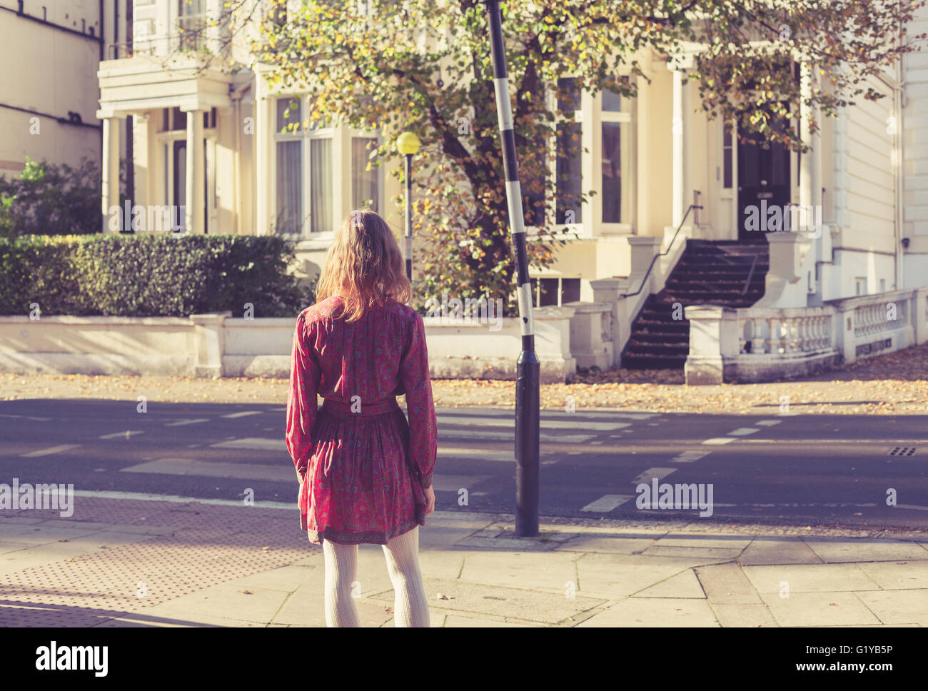 A young woman is standing in the street in a residential area of the ...