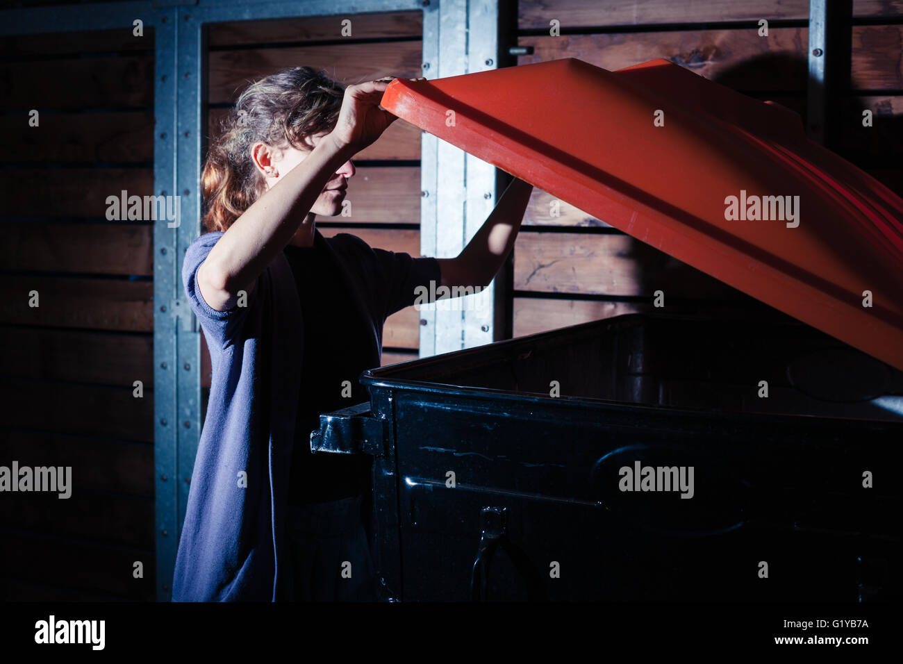 A young woman is looking inside a large bin at night Stock Photo - Alamy