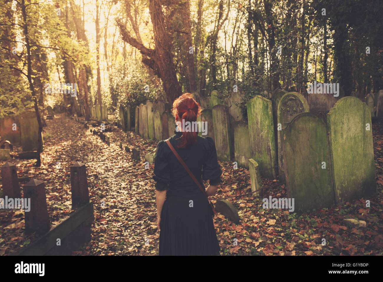 A young woman is walking amongst the tombstones in a cemetery Stock ...