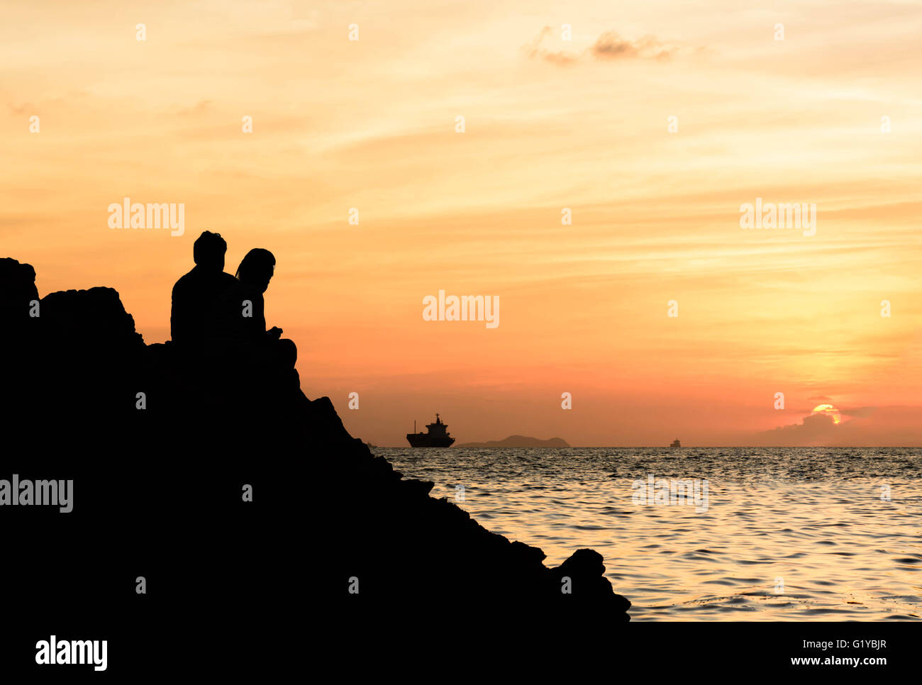 Silhouette of a couple watching a colorful sunset Stock Photo - Alamy