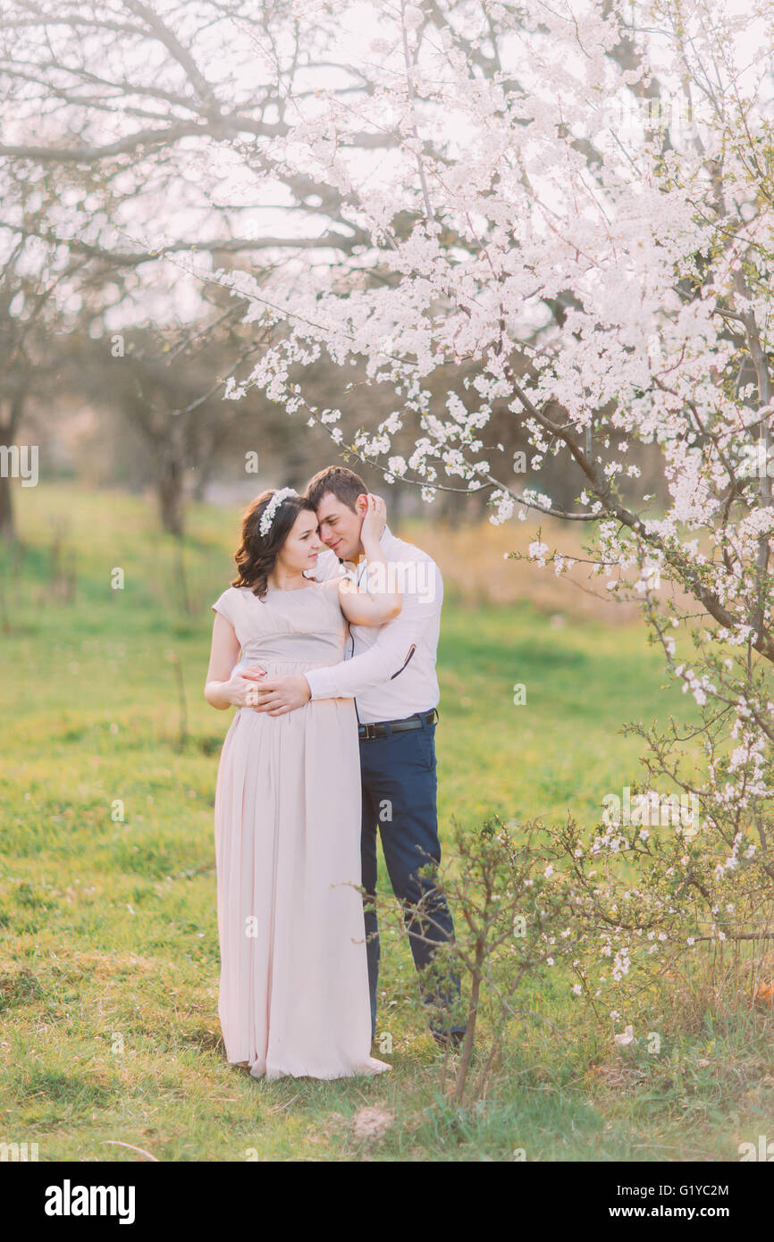 Love and tenderness. Beautiful young loving couple embracing in blossom ...