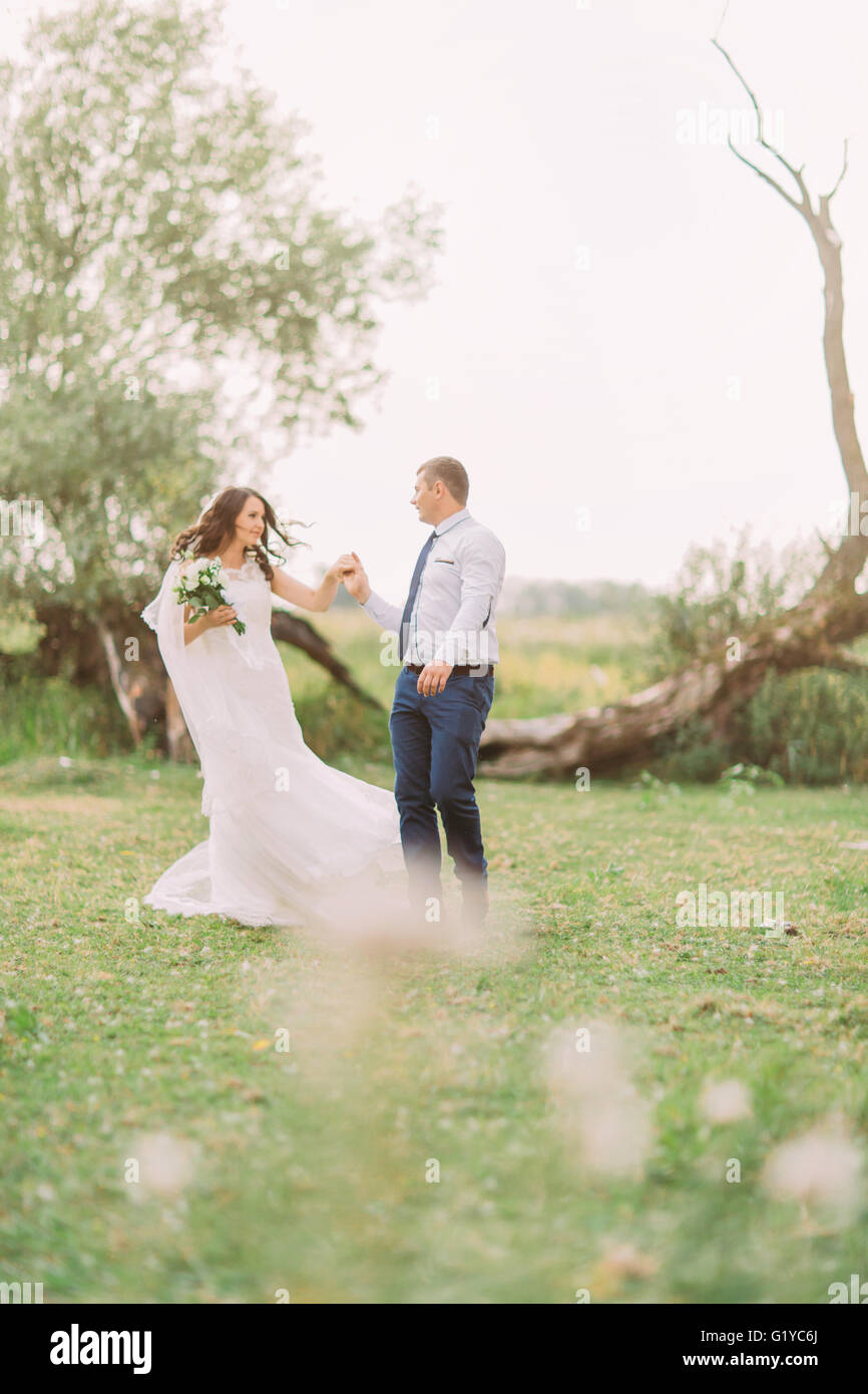 Happy stylish bride with elegant groom dancing on the background of ...
