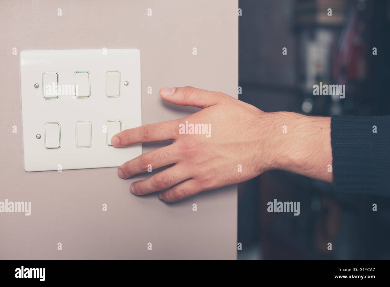 A young man's hand is switching on a light switch at home Stock Photo ...