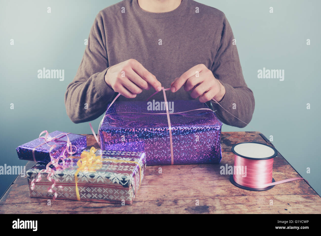 A young man at a table is wrapping presents Stock Photo - Alamy