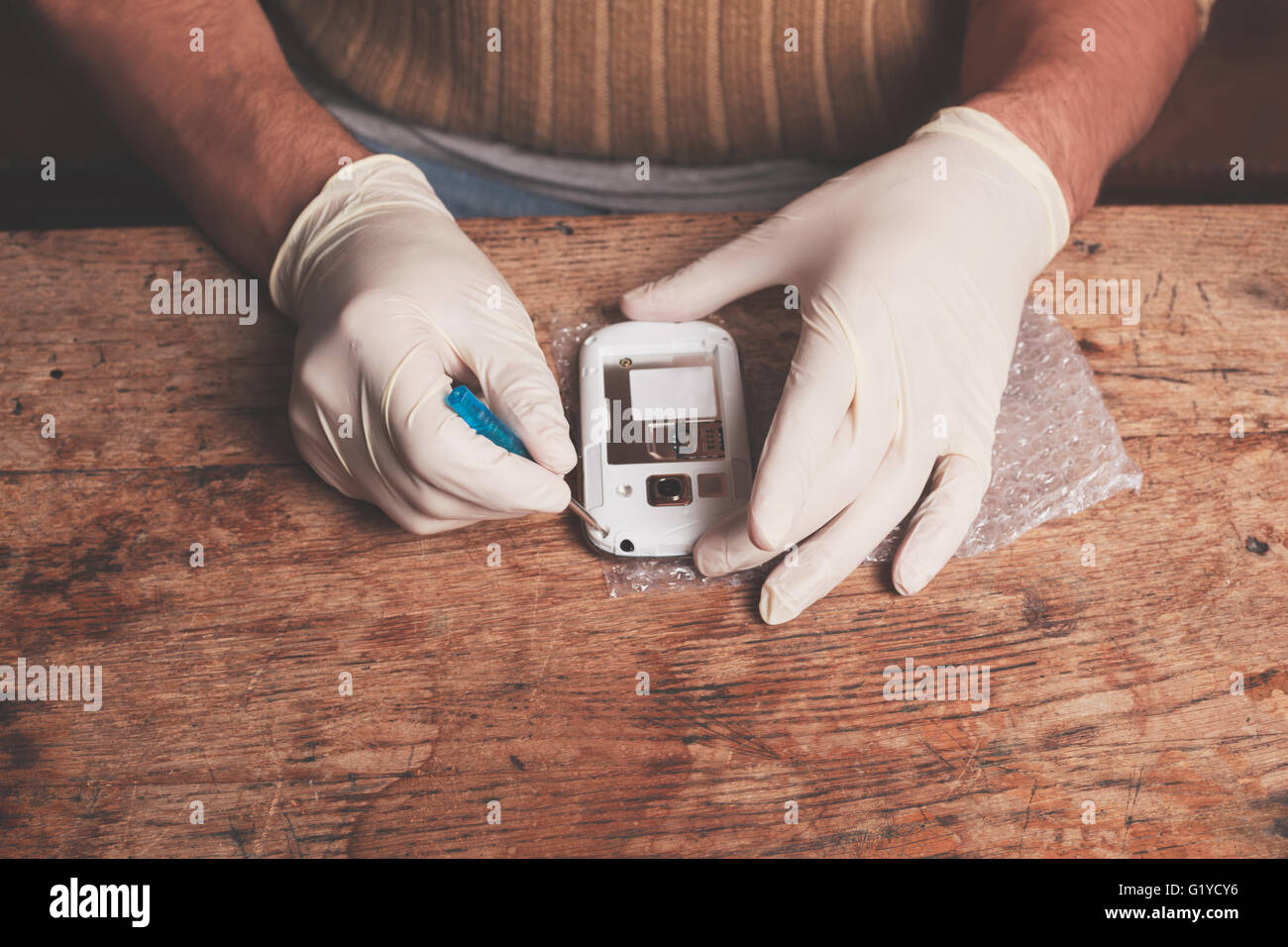 A technician is fixing and replacing the broken screen on a smart phone ...