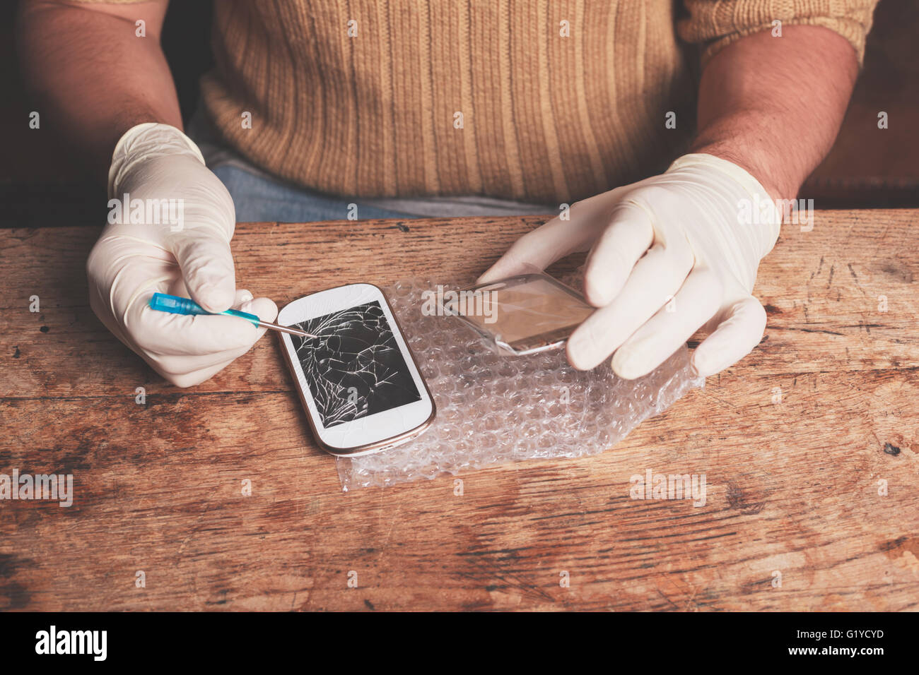 A technician is fixing and replacing the broken screen on a smart phone ...