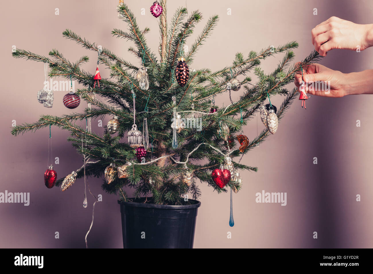 Hands decorating a christmas tree with all kinds of colorful things ...