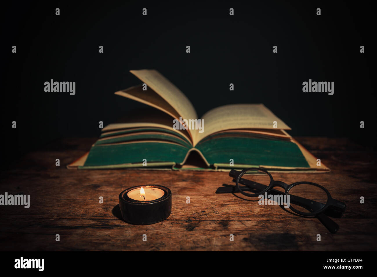 An open book and some glasses at night by candle light Stock Photo - Alamy