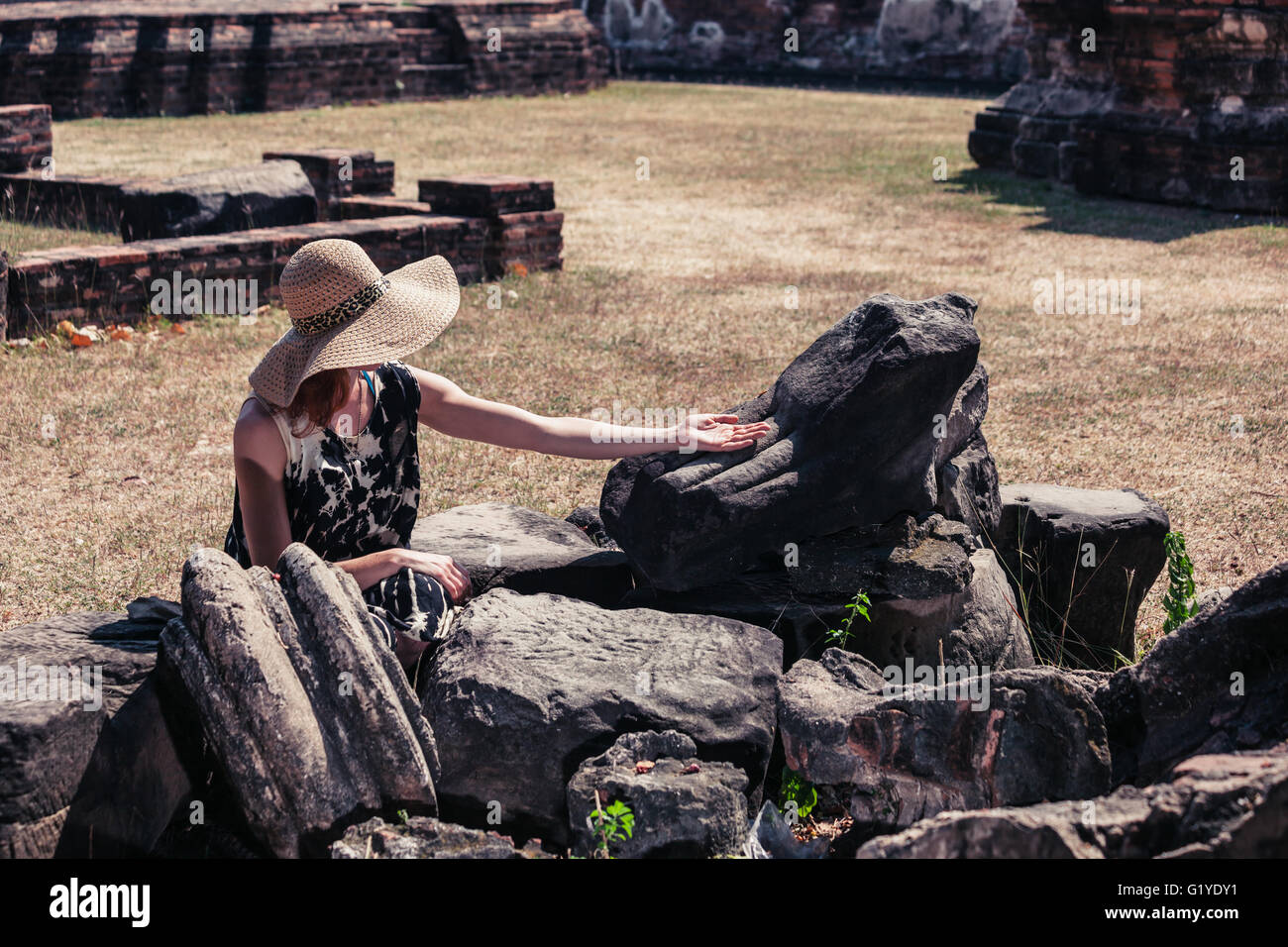 A young woman is touching the ancient ruins of a buddha statue Stock ...
