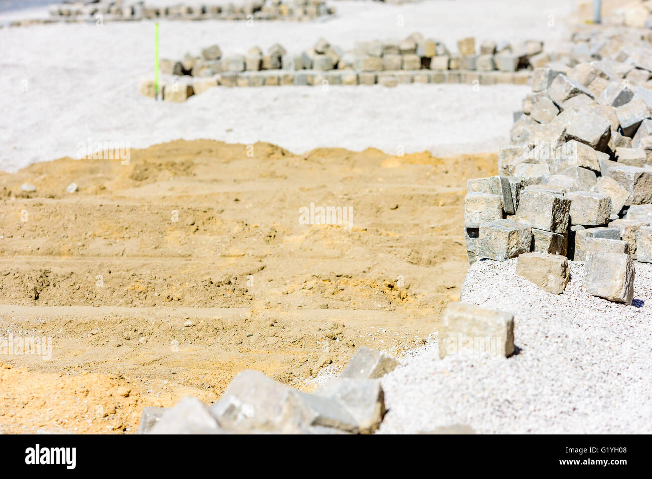 Piles of granite cubes or blocks are ready to be set in the road. Sand ...