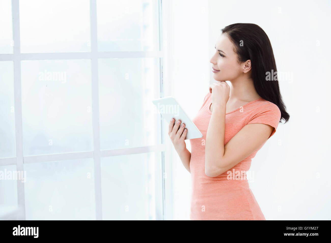 Beautiful young woman near window Stock Photo - Alamy