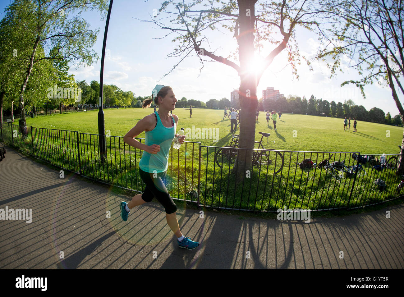 A female runner runs with a late afternoon sun in a london park Stock ...