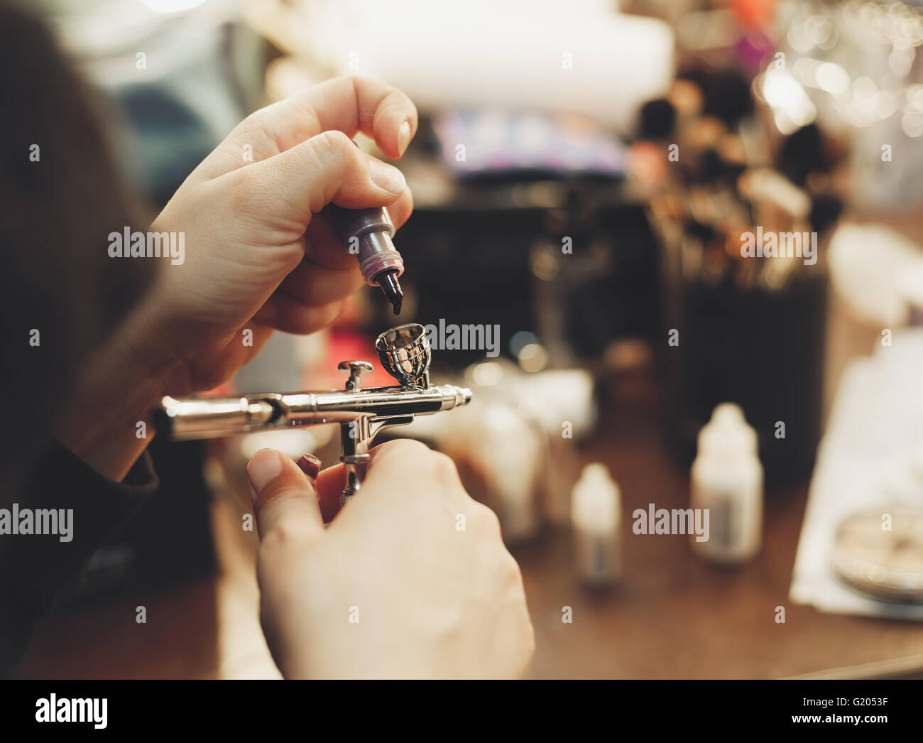 Make up artist filling the airbrush with liquid paint. Fading film ...