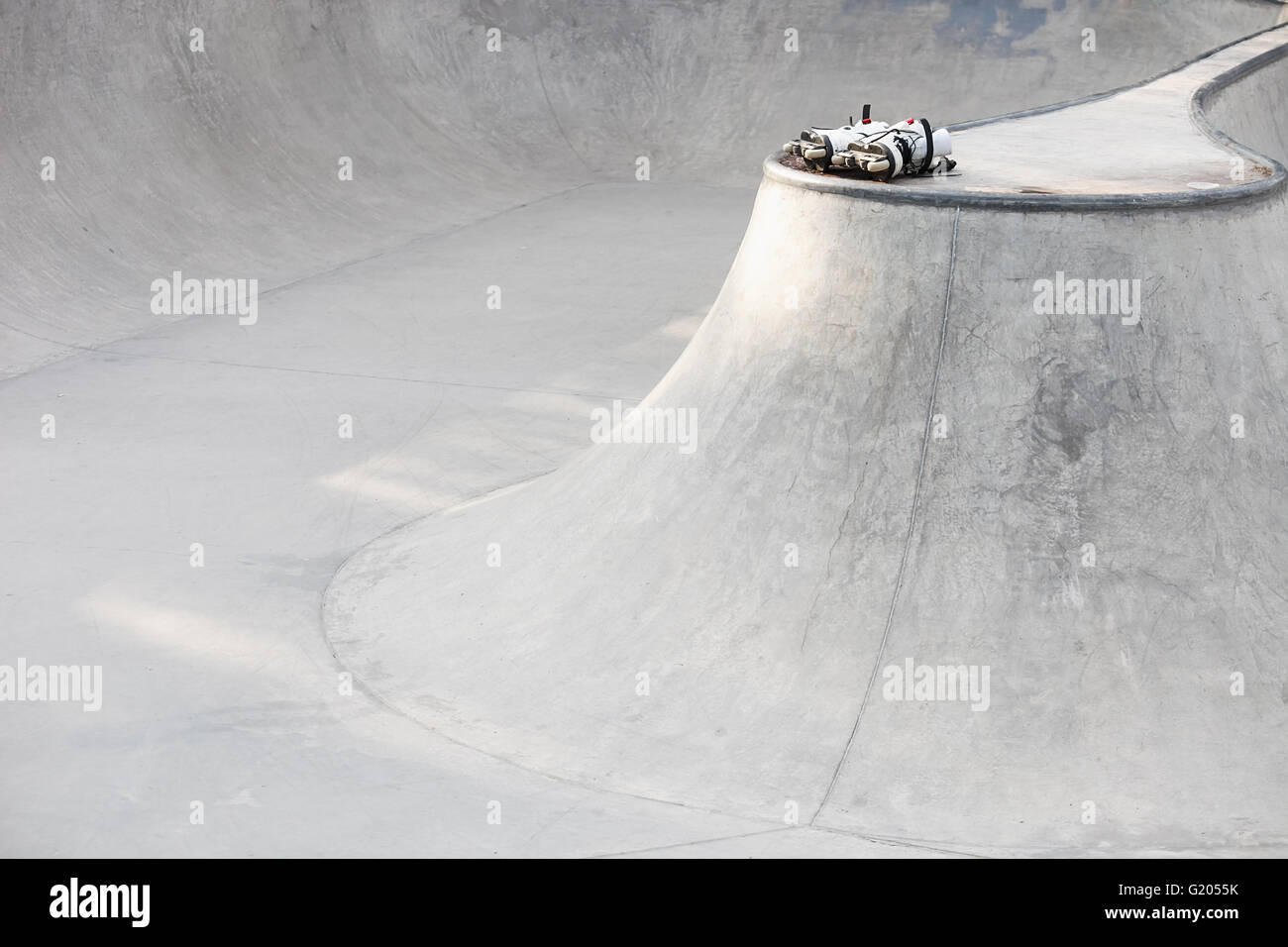 Aggressive inline skates lying on concrete ramp in outdoor skate park ...