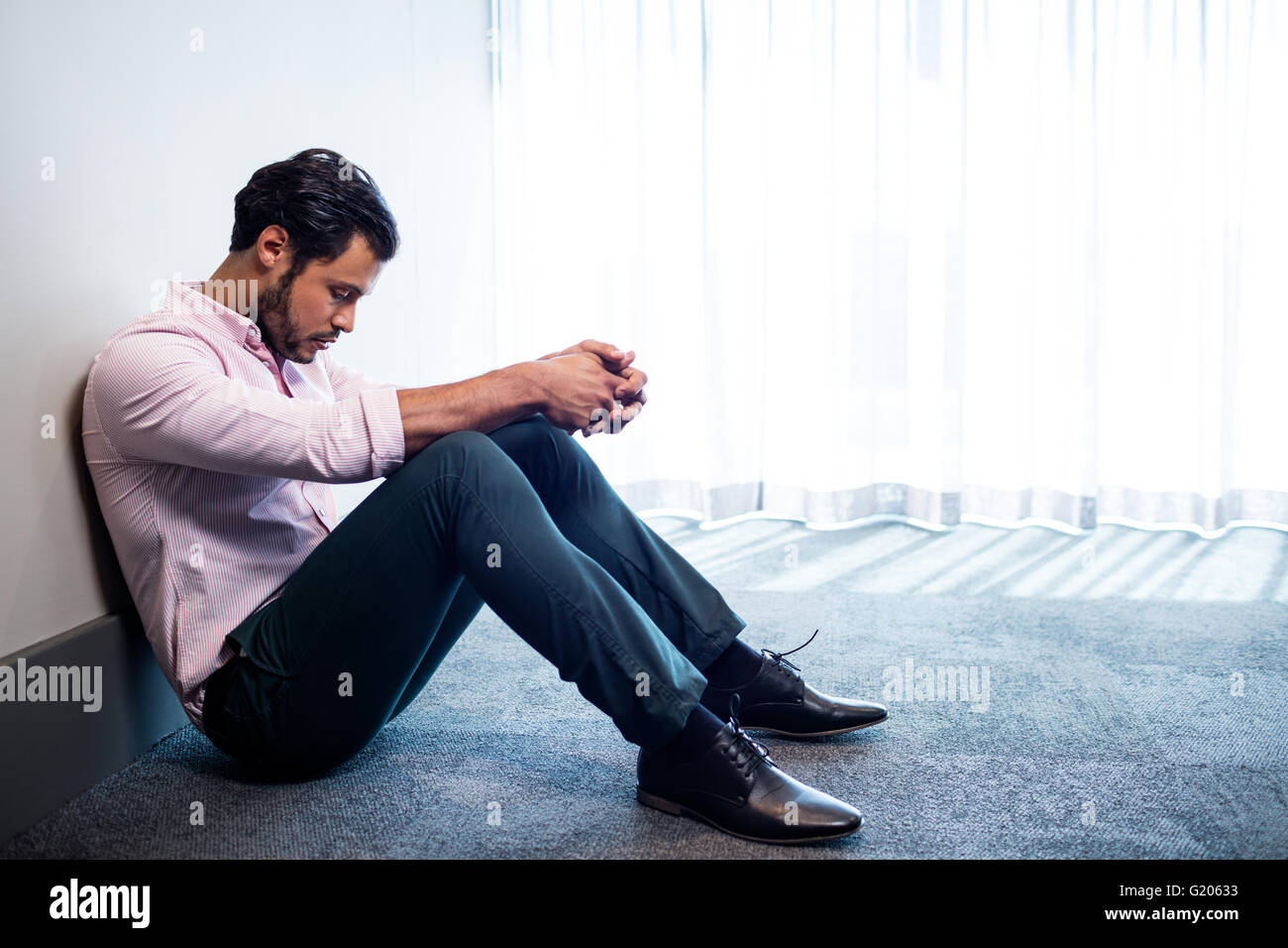 Depressed businessman sitting against a wall and looking down Stock ...
