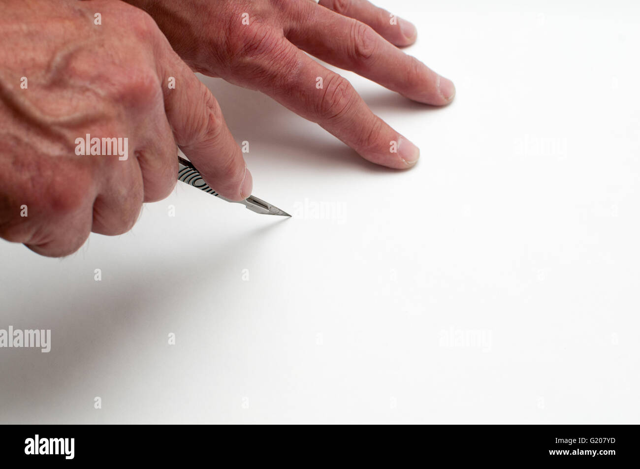 An artist cutting white paper with a craft knife and measuring with a ...