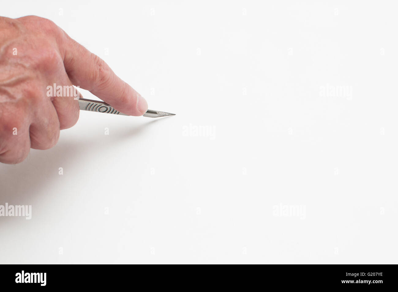 An artist cutting white paper with a craft knife and measuring with a ...