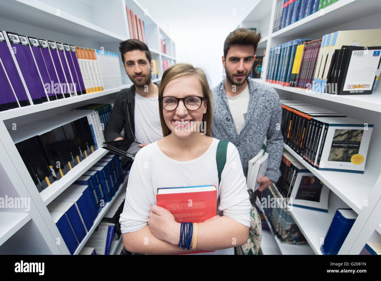 happy students group in school library selecting books to read and ...