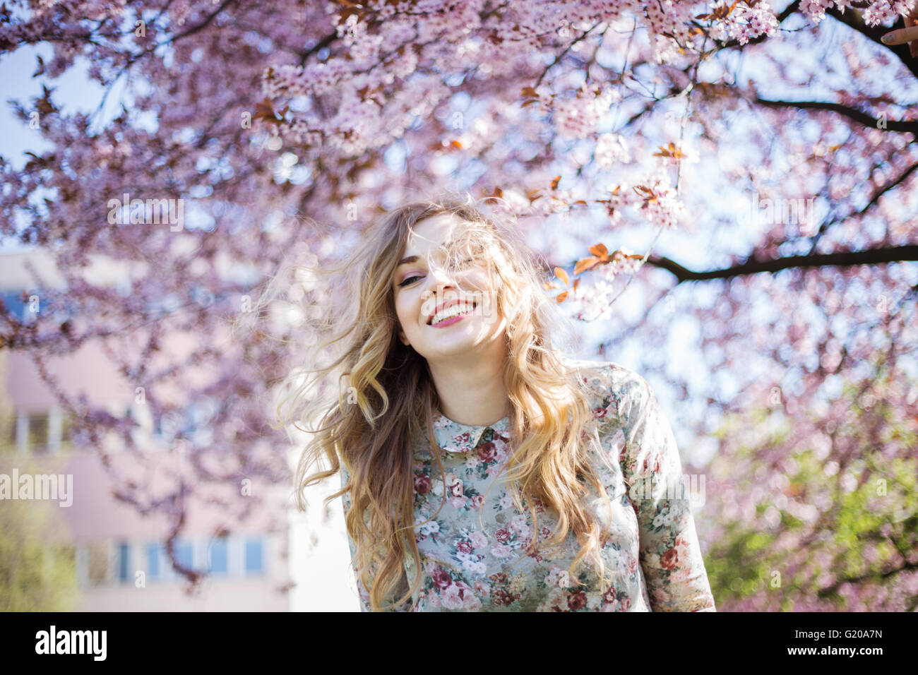 Young woman smiling in front of the spring blossom tree Stock Photo - Alamy
