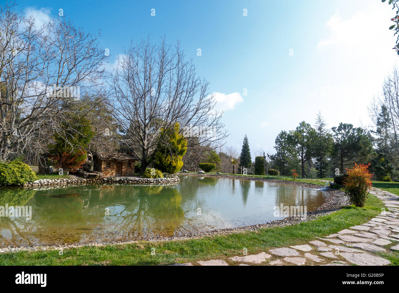 View of a small lake with a wooden house inside in a park with big ...