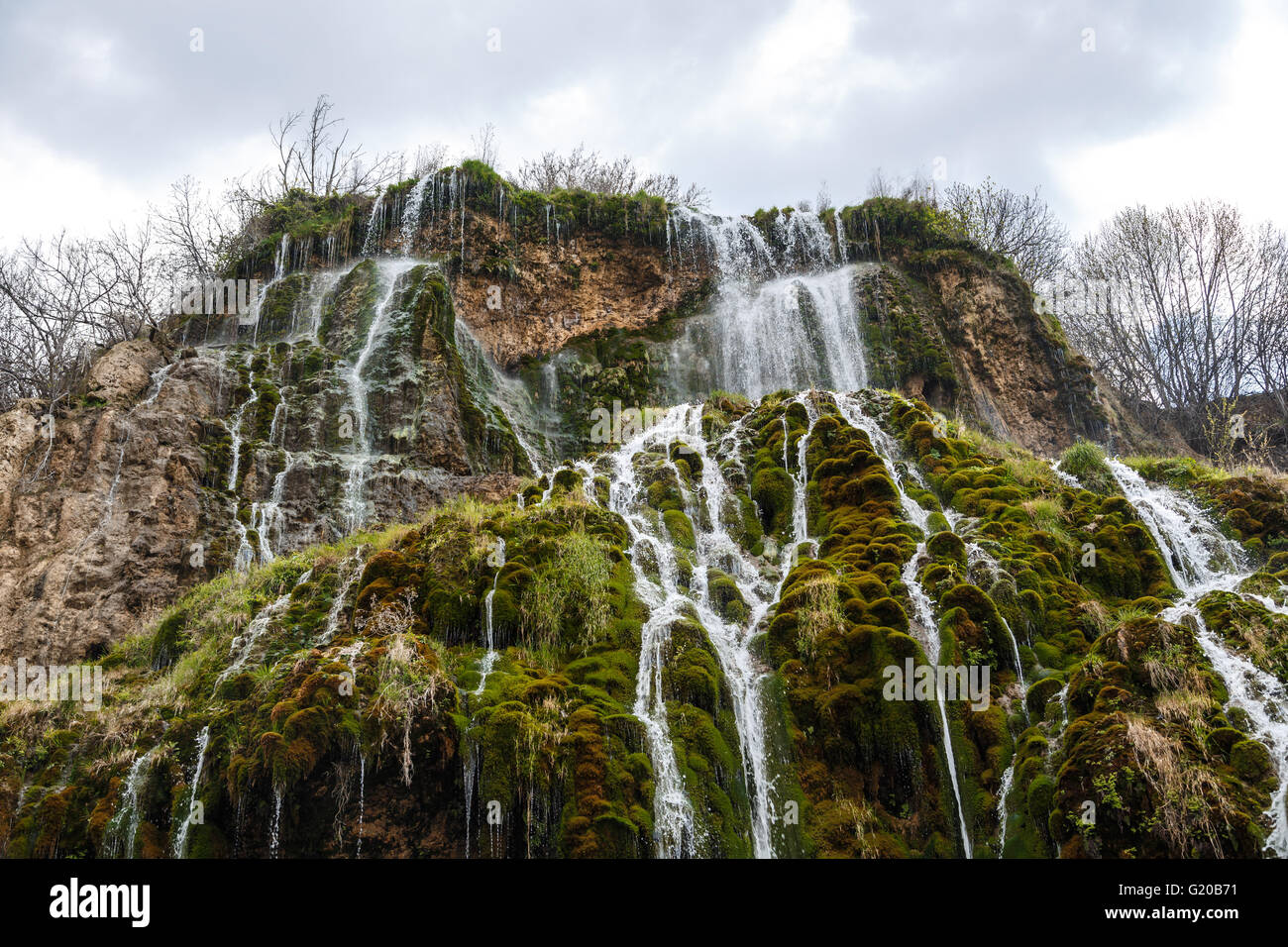 View of a waterfall, flowing from high inside meadow area, with green ...