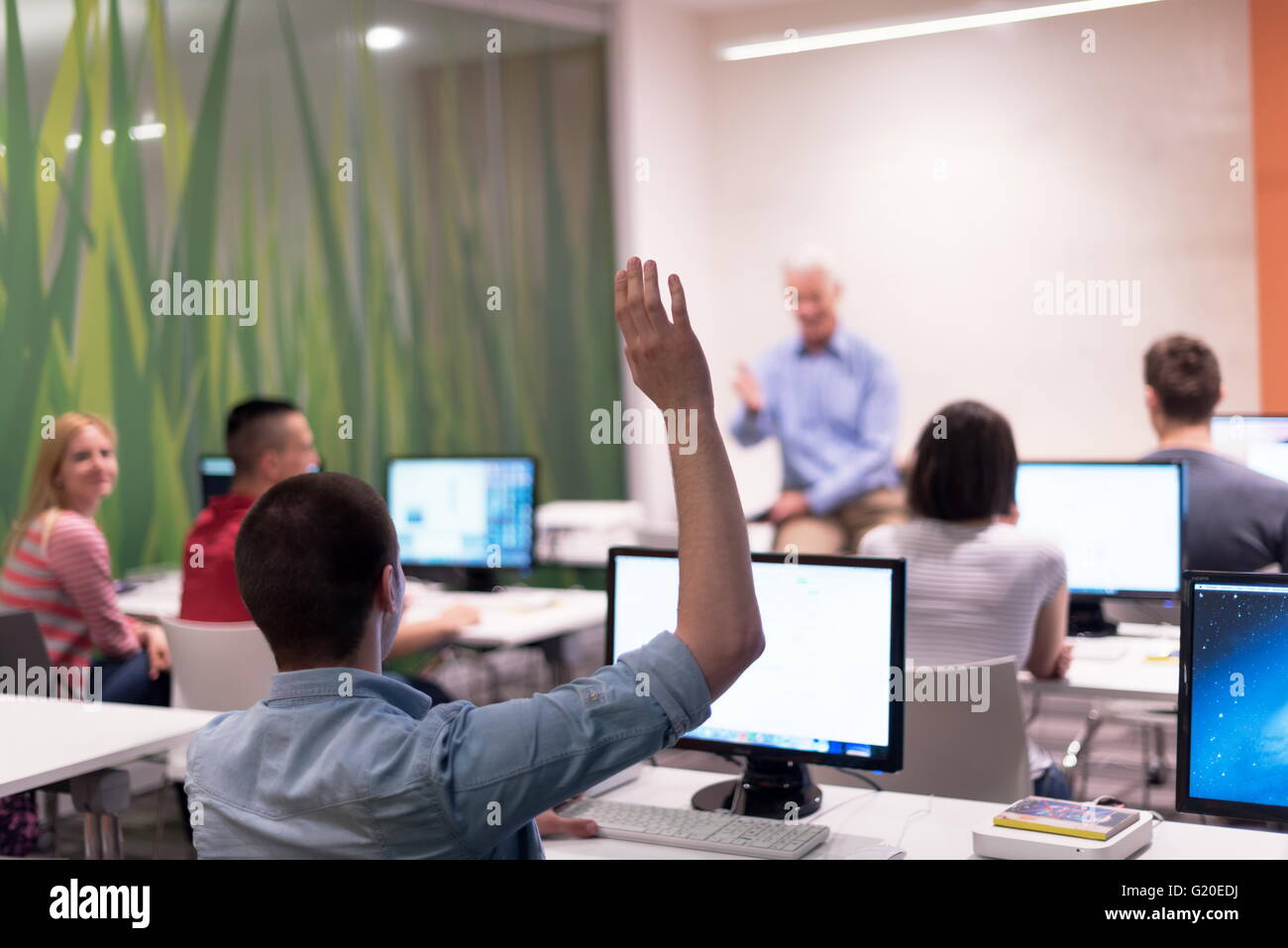 student answering a question in classroom, mature teacher and students ...