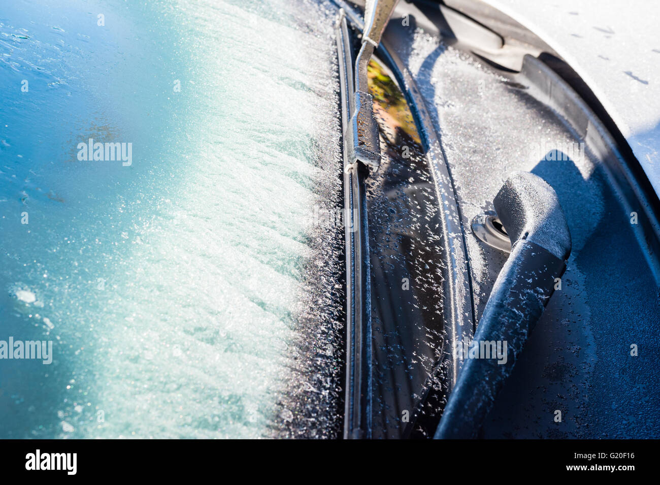 Car windshield and wipers covered in frost in winter, partially shaded ...