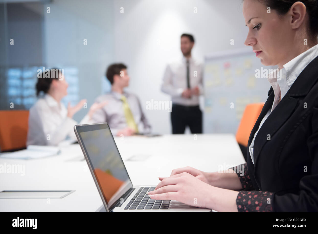 young business woman on meeting usineg laptop computer, blured group of ...