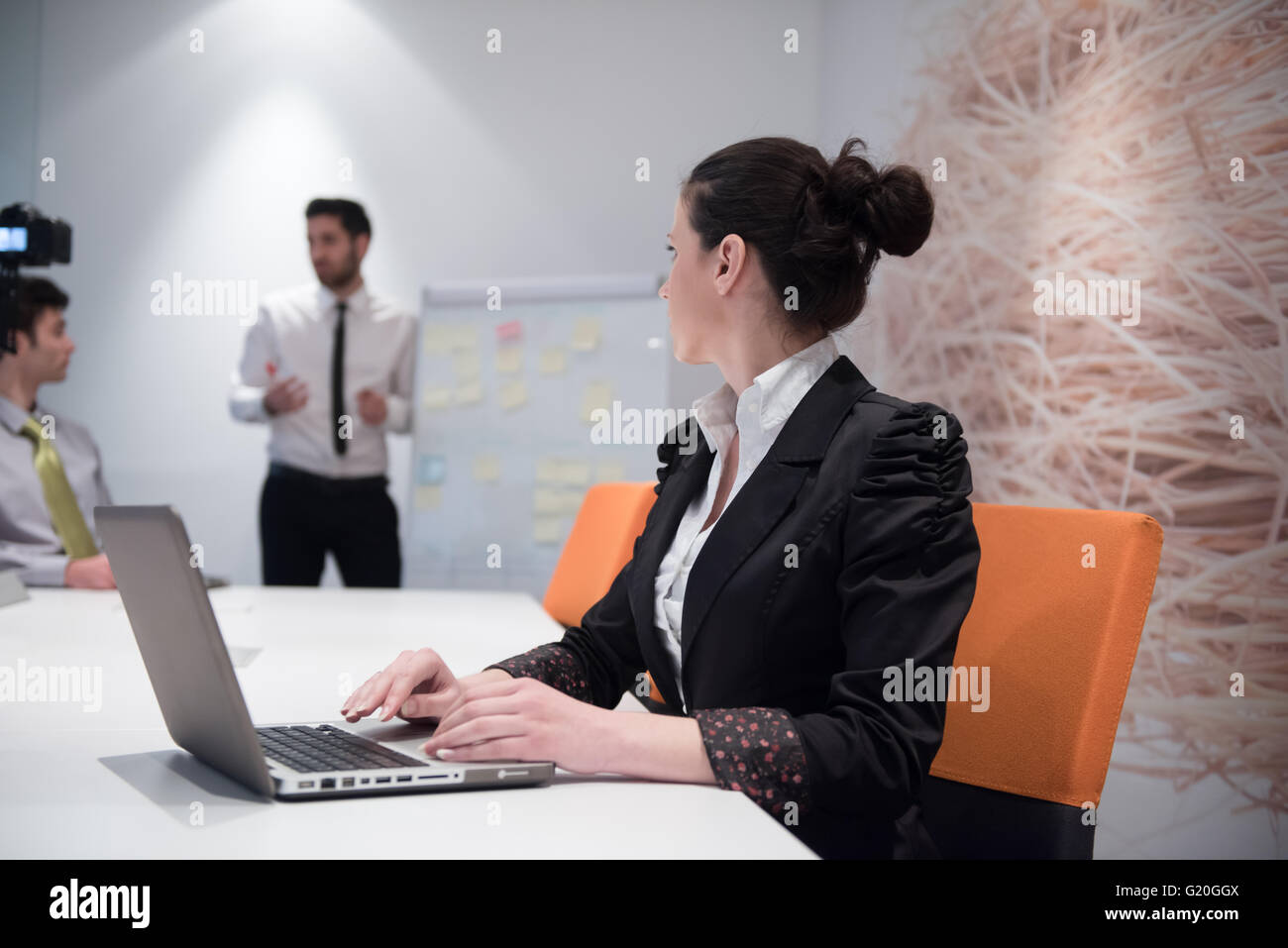 young business woman on meeting usineg laptop computer, blured group of ...