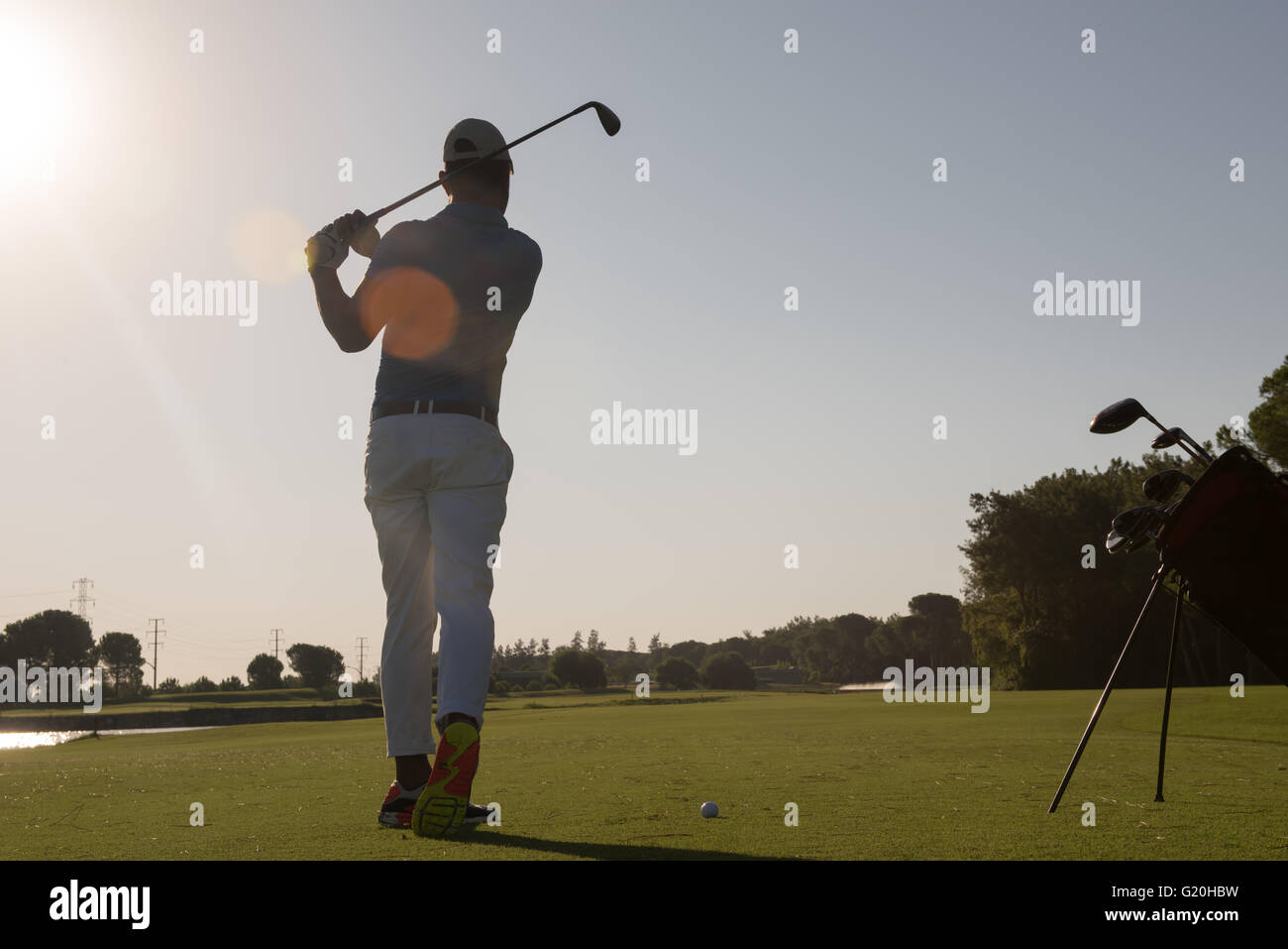 golf player hitting shot with club on course at beautiful morning with ...