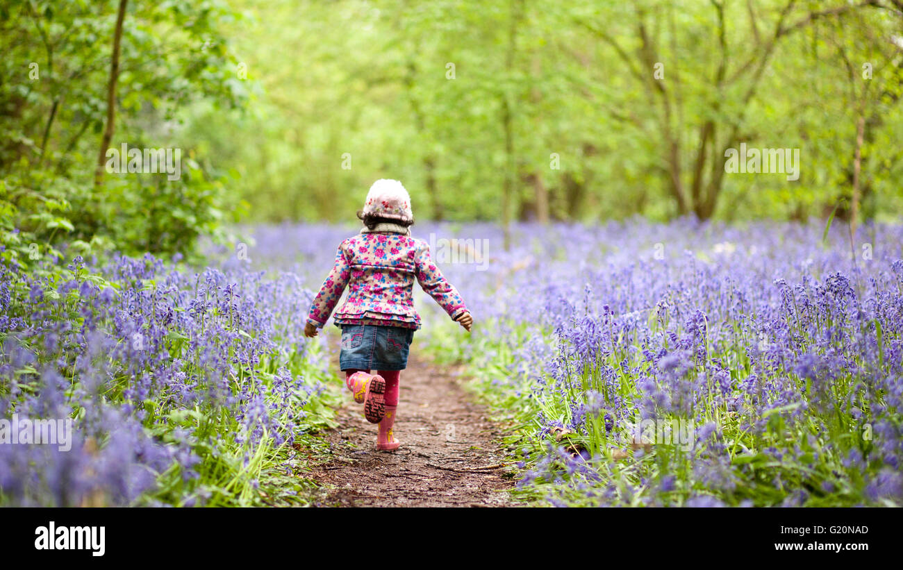 Girl running through purple bluebell flower field having fun on a sunny ...
