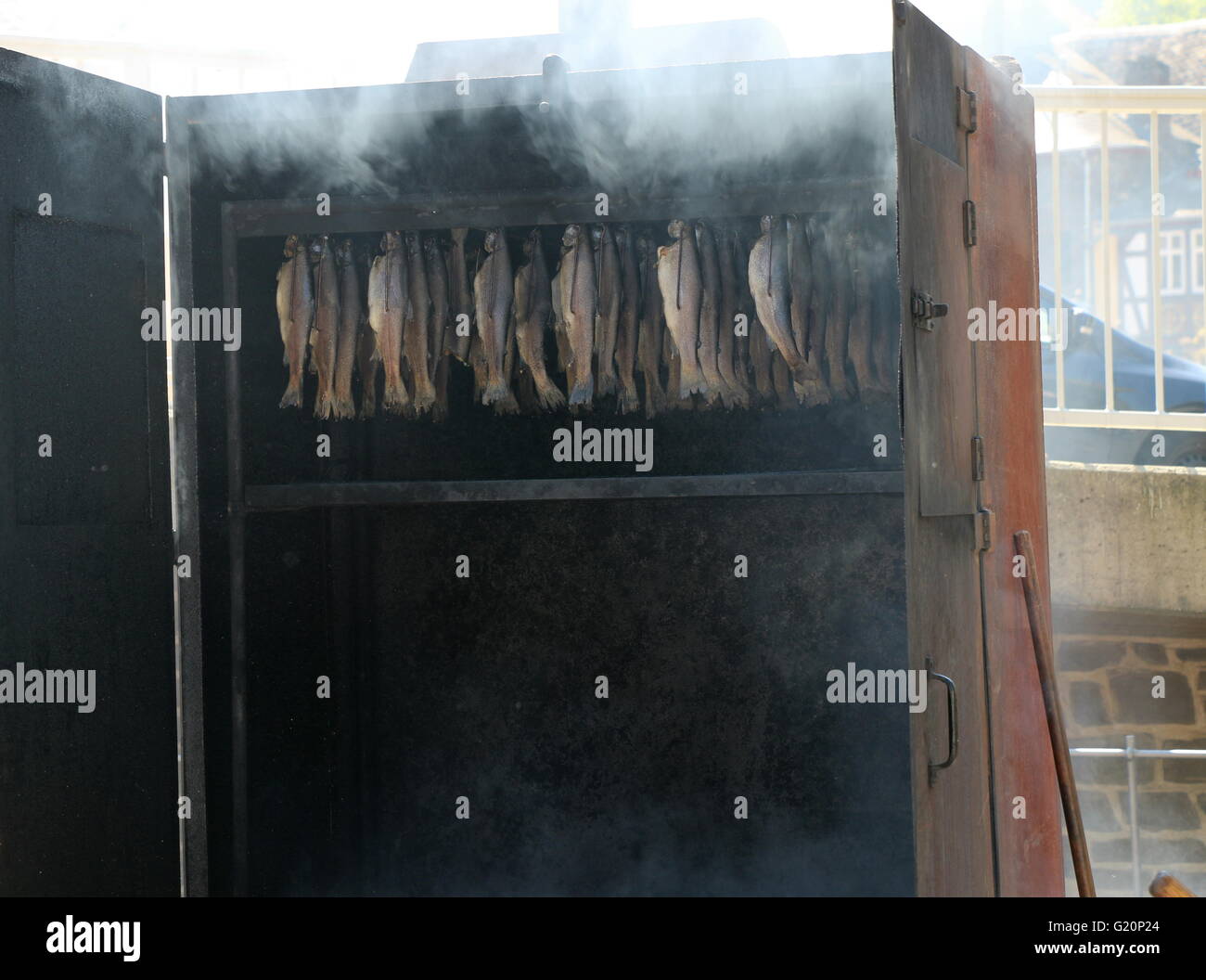 Fish being smoked in an outdoor metal cooker, farmers market, Germany ...
