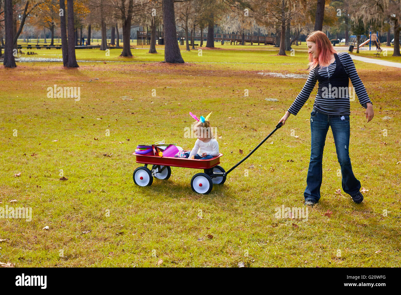 Kid girl and mother walking in the park with pull cart Stock Photo - Alamy