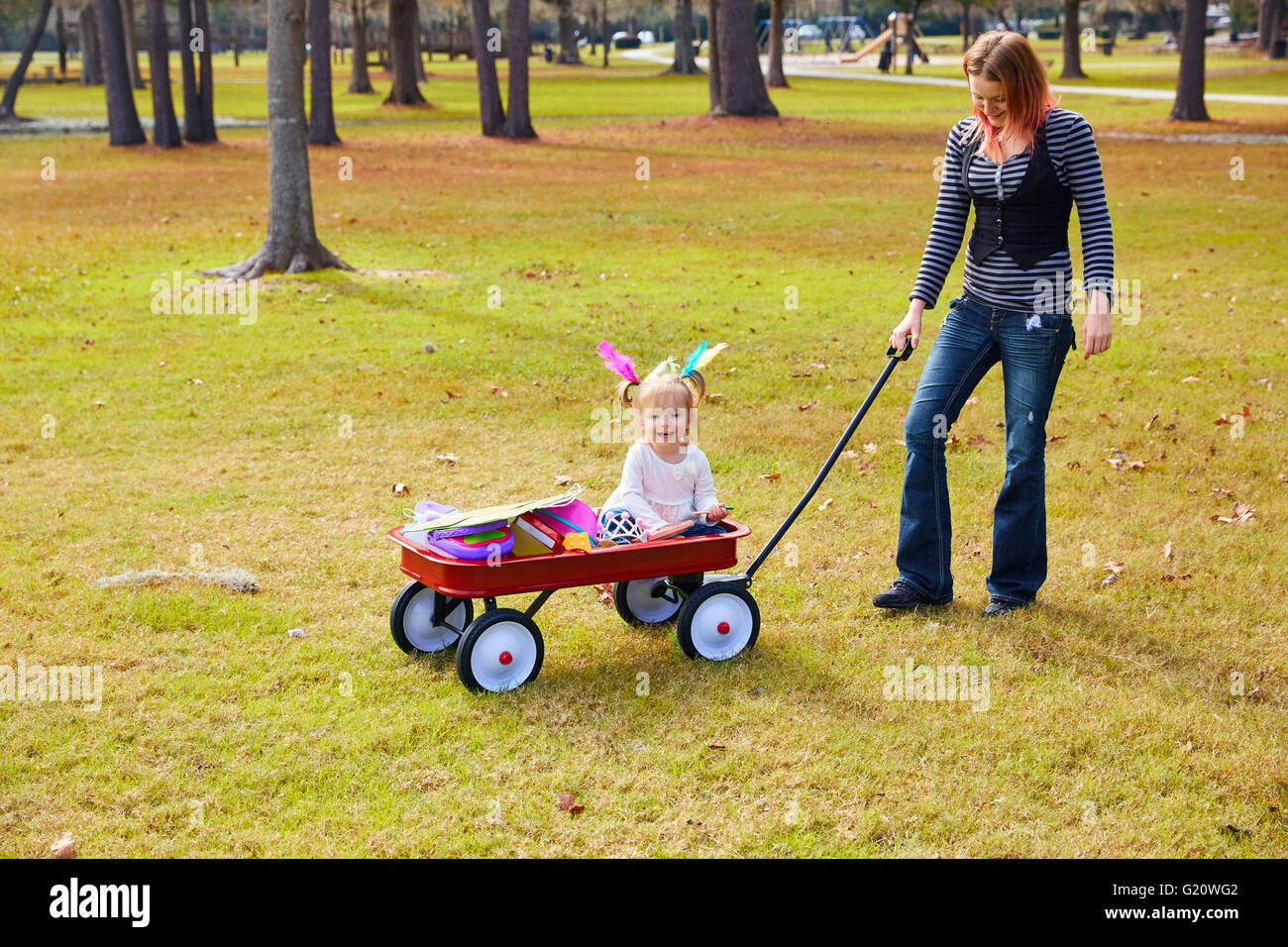 Kid girl and mother walking in the park with pull cart Stock Photo - Alamy