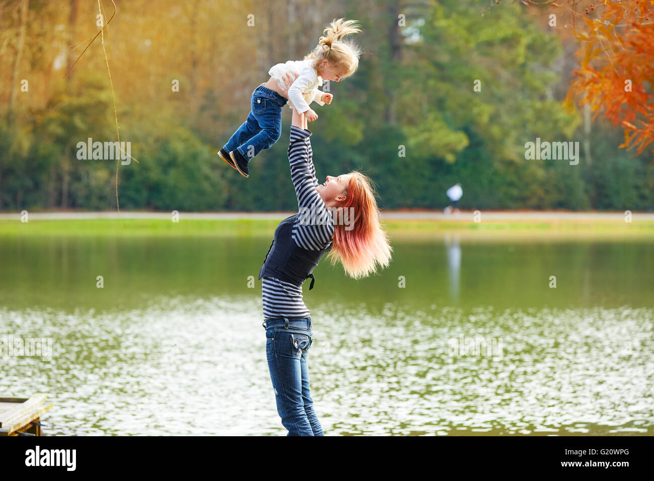 Mother playing throwing up baby girl daughter in the park lake Stock ...