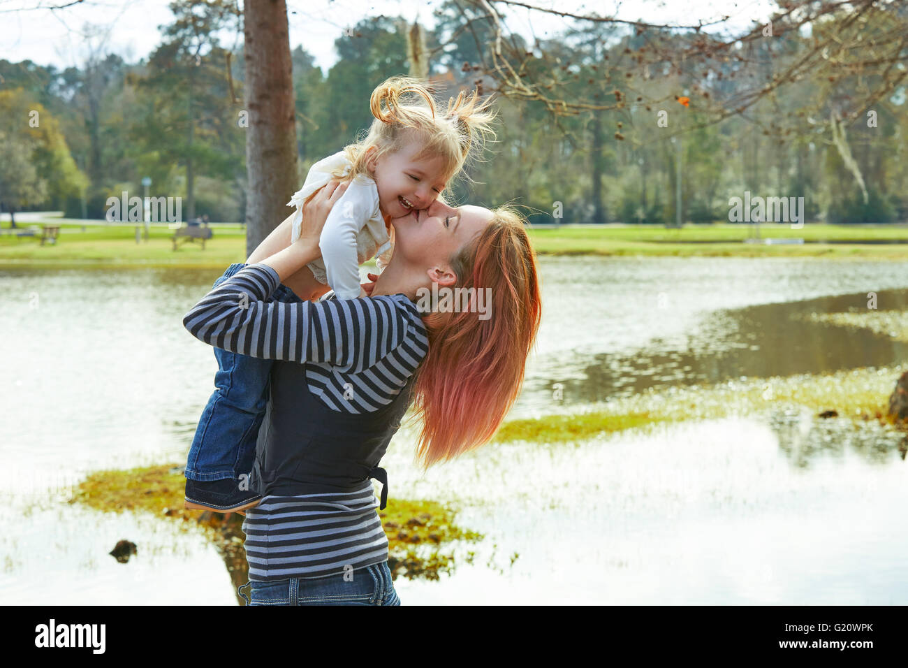Mother playing throwing up baby girl daughter in the park lake Stock ...