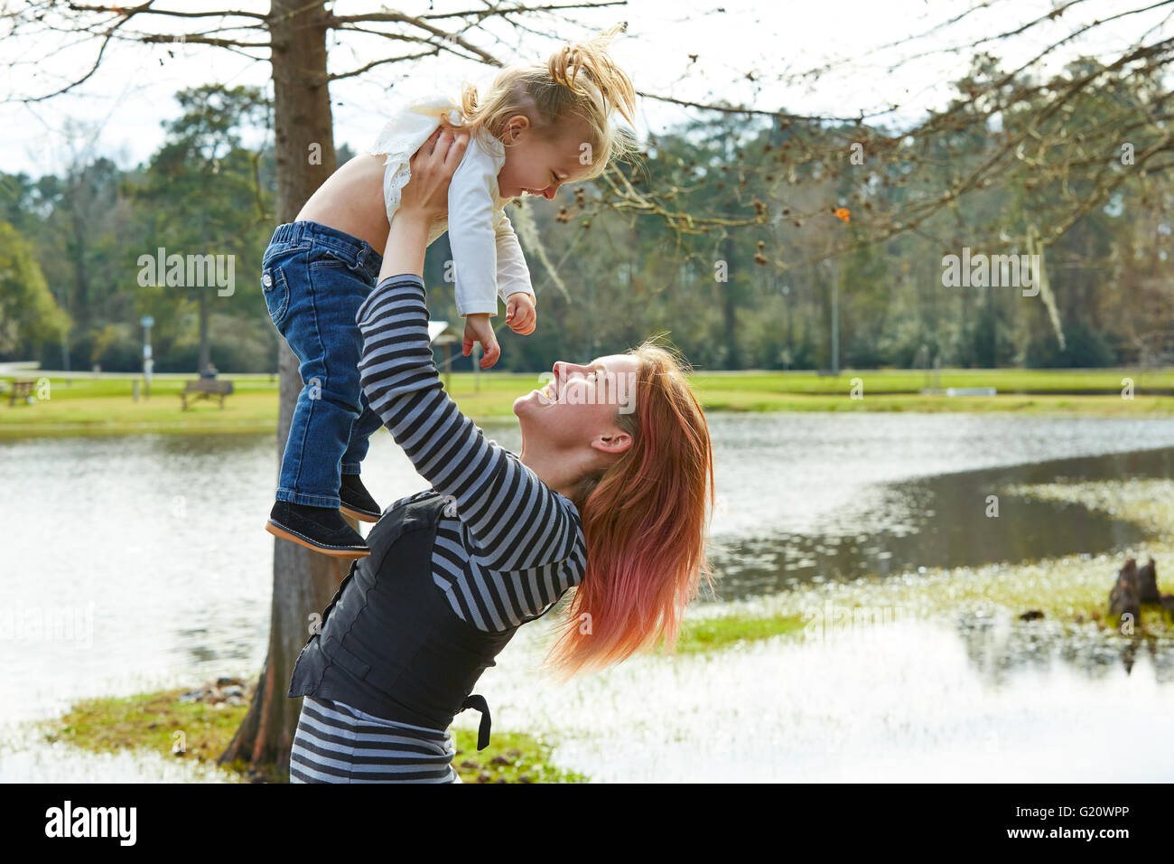 Mother playing throwing up baby girl daughter in the park lake Stock ...