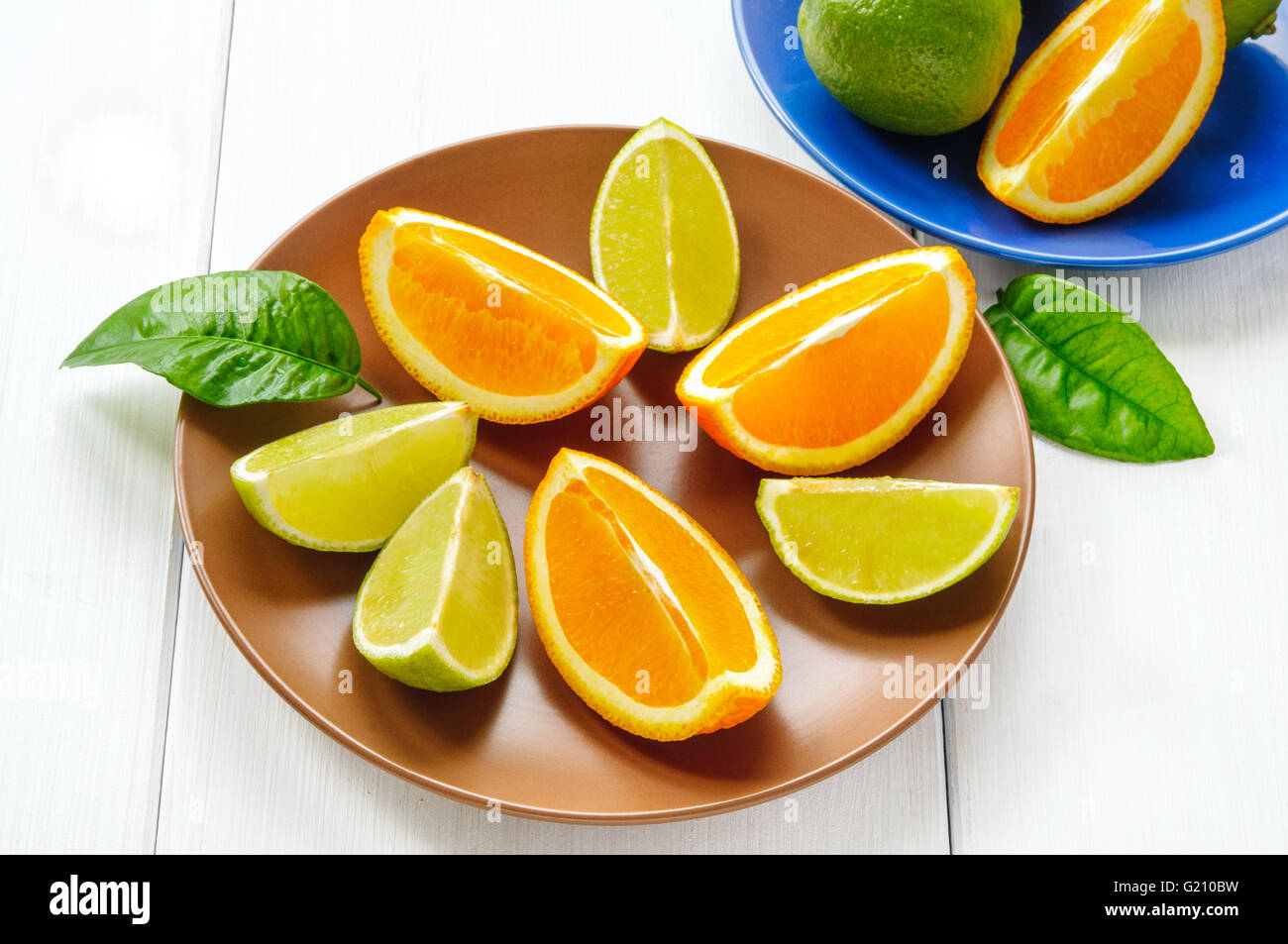 Orange segments with leaves on white wooden surface Stock Photo - Alamy