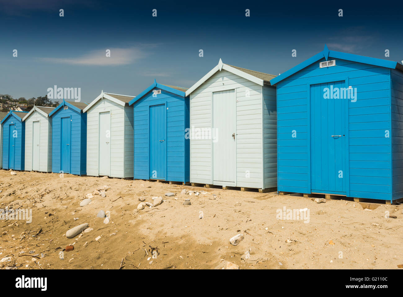 Blue beach huts in row against sky and sand Stock Photo - Alamy
