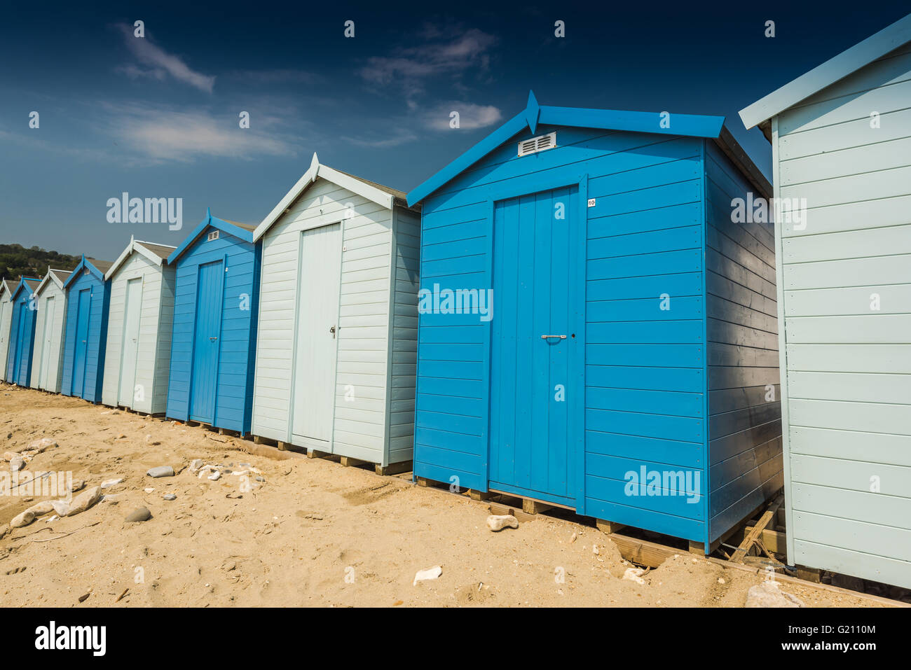 Blue beach huts in row against sky and sand Stock Photo - Alamy