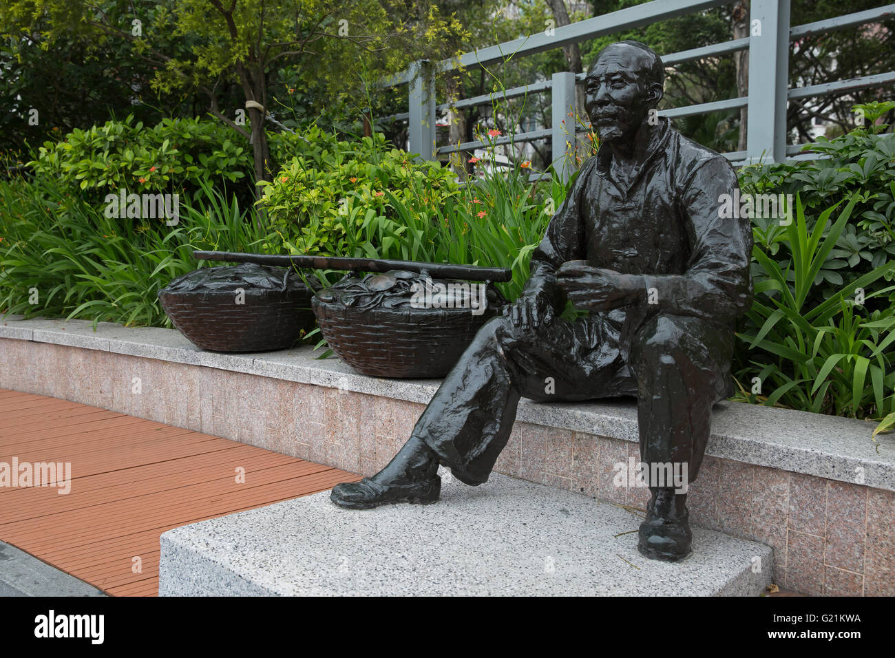A statue of an old fisherman with his catch in baskets on a wall in ...