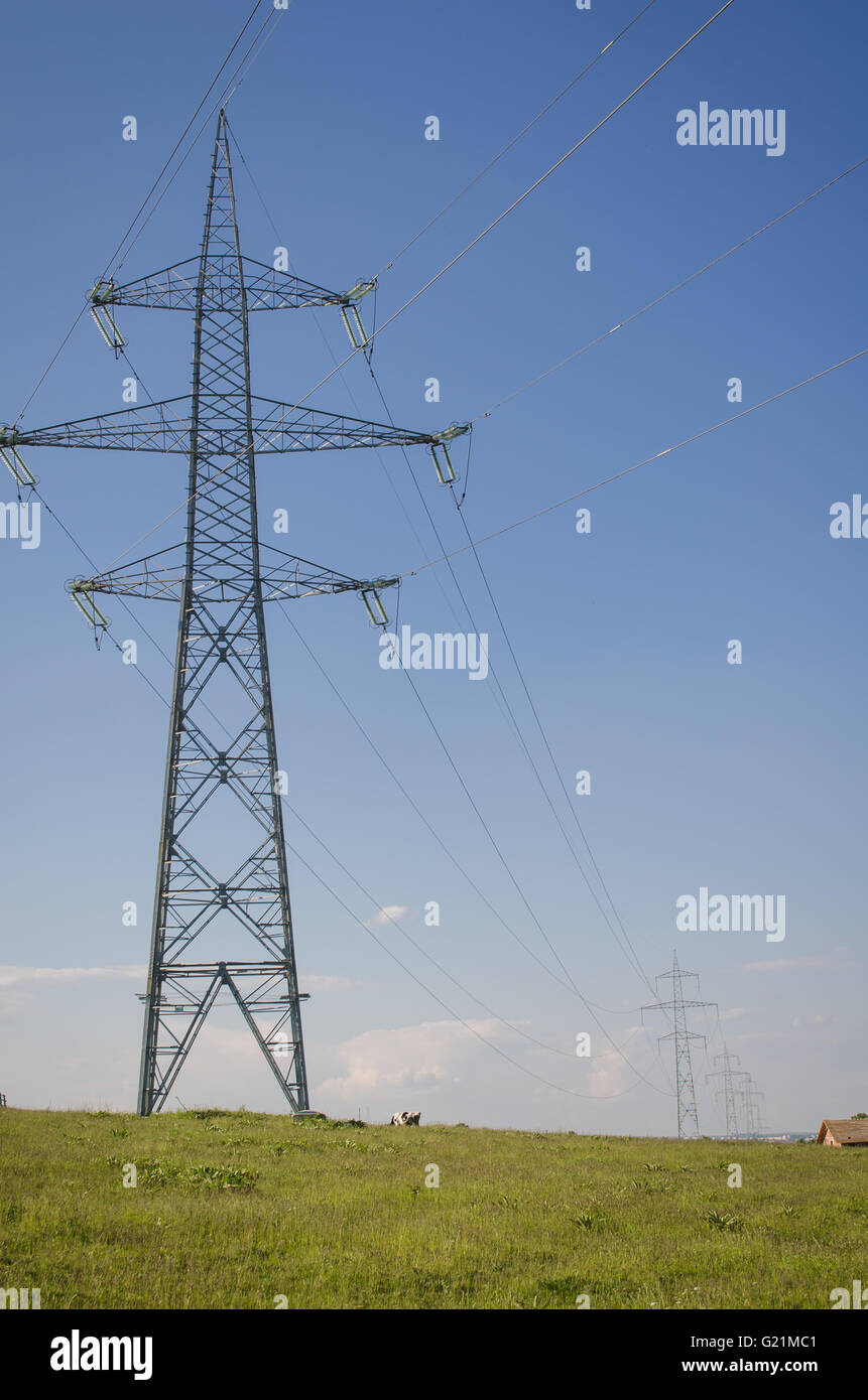 Electricity transmission pylon silhouetted against blue sky at dusk ...