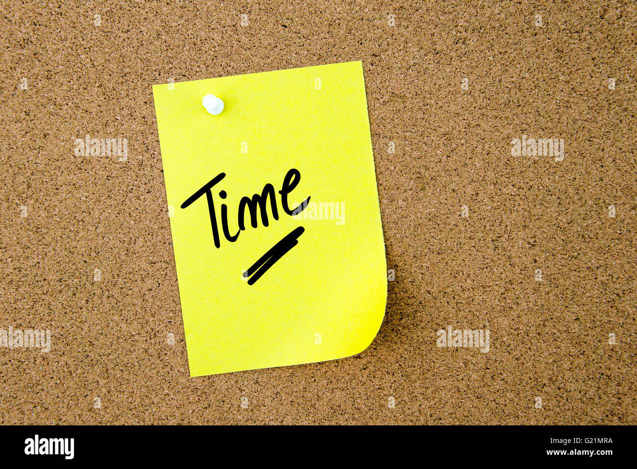 Time written on yellow paper note pinned on cork board with white ...