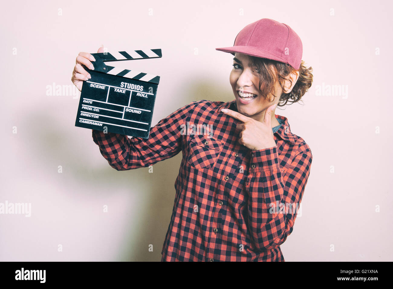Girl in red shirt and cap smiling and showing movie clapper on white ...